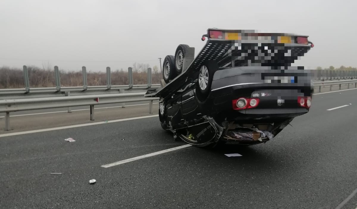 Mașină răsturnată cu roțile în sus, cu tot cu platformă, în mijloc de ...